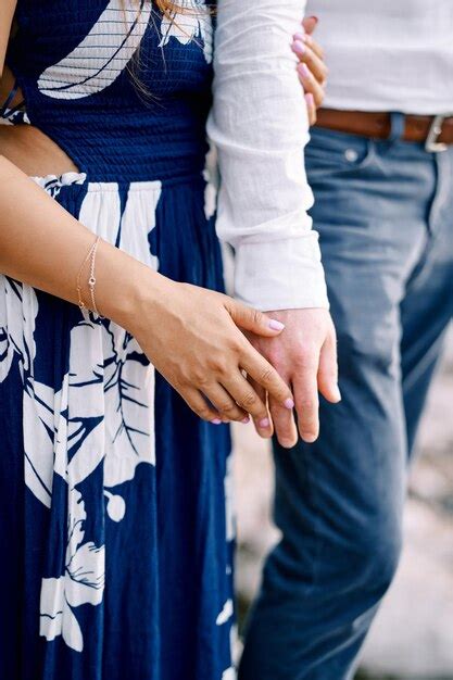 Premium Photo Woman Stands Hugging Man Arm And Touching His Palm With Her Palm Cropped Faceless