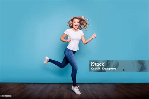 전체 길이 바디 크기 보기 좋은 사랑 스러운 매력적인 여성 쾌활 한 명랑 낙관적 미친 물결 모양의 레이디 캐주얼 흰색 T 셔츠에 빠르게 고립 된 파란색 배경 위에 실행 T