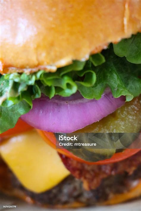패스트 푸드 테이크 아웃 베이컨 치즈 버거 쇠고기 패티를 곁들인 버거 롤빵 베이컨 러셔 녹은 치즈 얇게 썬 토마토 붉은 양파 절인 작은 오이와 양상추 전경에 초점 0명에
