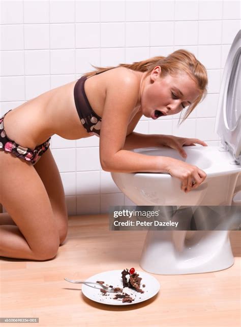 Teenage Girl With Chocolate Cake Vomiting Into Toilet Bowl High Res