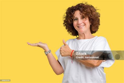 아름 다운 중간 어른 고위 여자 엄지손가락 행복 하 고 밝은 미소와 제스처를 확인 하 고 격리 된 배경 표시 팜 손 위에 흰색 T셔츠를 입고 T 셔츠에 대한 스톡 사진 및