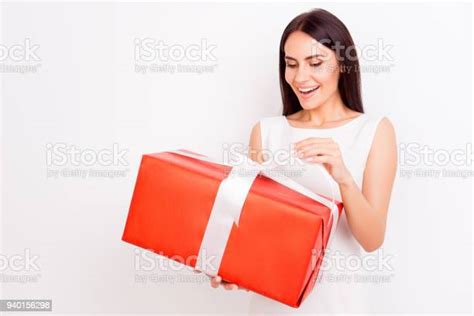 행복 한 놀된 화려한 갈색 흰색 바탕에 큰 빨간 선물 상자를 들고 있다 그녀는 미소 순수 배경에 흰색 옷을 입고 경외감에 대한