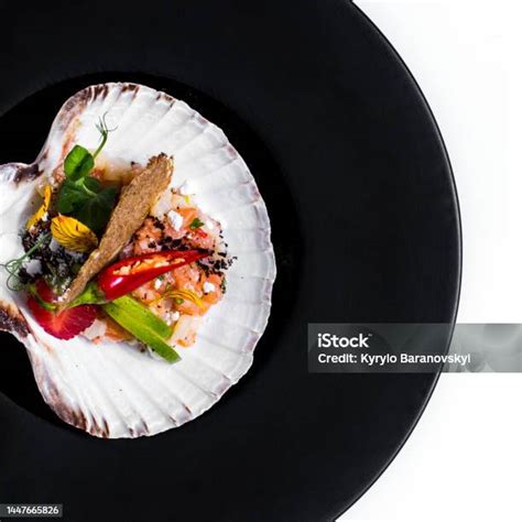 Arugula 잎 고추 식용 꽃잎 딸기 해바라기 씨와 마이크로 그린 및 호밀 빵 칩과 연어 타르타르 음식은 껍질에 있고 껍질은 검은 색의 깊은 접시에 있고 접시는 흰색