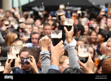 Image Of Hands In A Crowd Holding Pints Of Guinness In The Air During The Arthurs Day