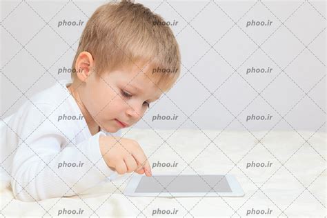 عکس با کیفیت پسر بچه در حال کار با تبلت در پس زمینه سفید عکس با کیفیت