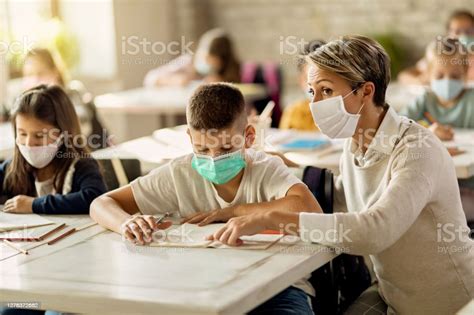 교실에서 수업 중에 보호얼굴 마스크를 쓰고 있는 여학생과 초등학생 보호 마스크에 대한 스톡 사진 및 기타 이미지 보호 마스크 교사 교육 관련 직업 학생 Istock