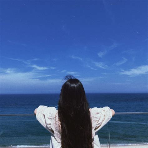 A Woman Standing On The Beach Looking At The Ocean