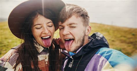 행복한 힙스터 커플은 셀카를 만들고 햇볕이 잘 드는 산 꼭대기에서 블루베리로 색칠된 혀를 보여줍니다 재미 있고 웃고있는 가족 여름 방학 텍스트 공간 사진