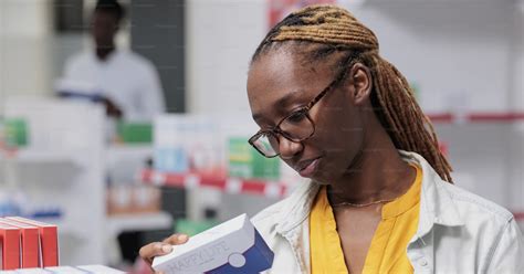 아프리카계 미국인 여성이 약국 선반에서 종합 비타민을 확인하고 태블릿 패키지를 보고 있다 영양 보충제를 선택하는 고객 약국 통로에 서 있는 고객 사진 Unsplash