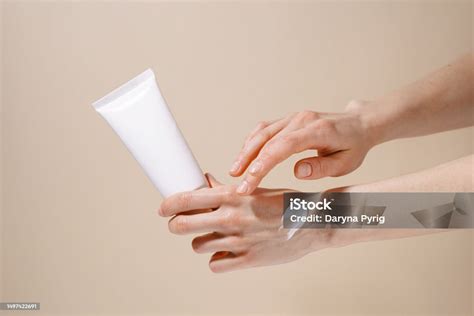 하얀 모형 항아리를 들고 베이지색 격리된 배경에 크림 샘플 견본을 바르고 있는 여성의 손 아름다움과 미학 보습 및 피부 관리의
