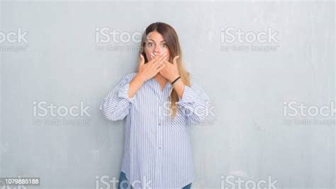 입 실수에 대 한 손으로 다루는 충격된 패션 비즈니스 옷을 입고 회색 그런 지 벽에 젊은 성인 여자 비밀 개념입니다 가리기에