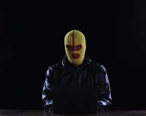 premium photo hooded masked hacker with laptop