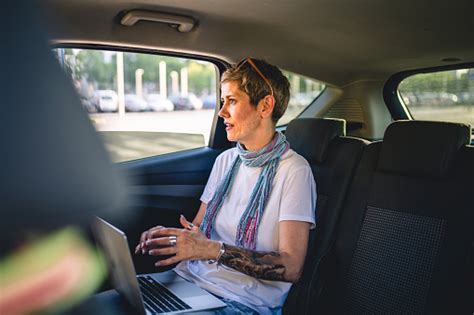 여름날 노트북 컴퓨터에서 일하는 자동차 뒷좌석에 앉아있는 성숙한 여성 백인 여성 한 명과 짧은 회색 머리 현대 관리자 또는 캐주얼 카피 공간을 착용하는 도로의 비즈니스