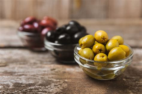 녹색과 검은색 올리브는 질감이 있는 오래된 나무 배경에 그릇에 나뭇잎이 있습니다 맛있고 건강한 음식 진미지중해식 주방 텍스트를 위한 위치입니다 카피스페이스 건강한 생활방식에