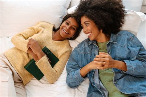 Black Girl And Her Mother Laughing And Talking While Lying On Bed Stock