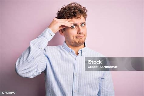 젊은 금발 잘생긴 남자 와 곱슬 머리 입고 줄무늬 셔츠 위에 흰색 배경 걱정 하 고 이마에 손에 문제에 대 한 스트레스 긴장과