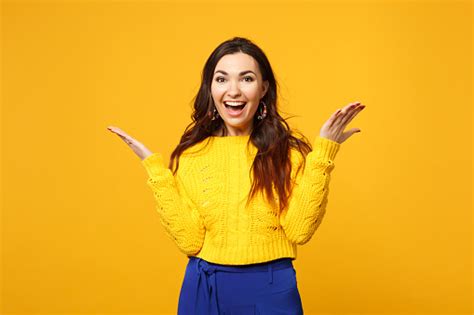 스웨터 블루 바지 카메라를 찾고 스튜디오에서 노란색 오렌지 배경에 고립 된 손을 확산 쾌활 한 젊은 여자를 놀라게 사람들은 진심으로 감정 라이프 스타일 개념입니다 복사