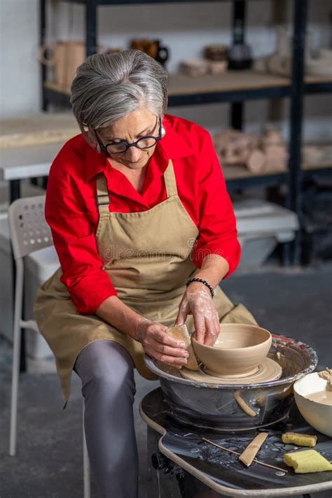 Woman Working On Potters Wheel Creating Clay Products At Her Workshop