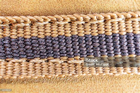 이미지는 복잡한 직물의 클로즈업을 보여주며 다양한 색상과 질감을 가진 두 개의 밴드를 보여주며 패션 인테리어 디자인 또는 전통적인 장인 정신에 사용되는 고품질 장인 정신을