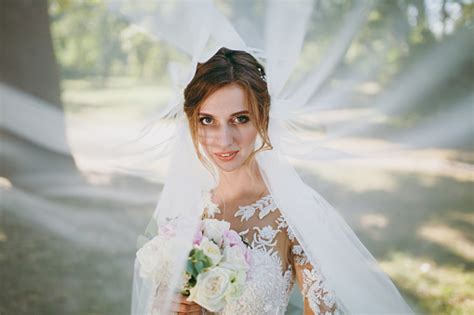 아름 다운 결혼식 Photosession입니다 흰색 레이스 드레스와 Weathery 화창한 날에 큰 녹색 정원에서 두리안 베일에 흰색과 분홍색 꽃의 꽃다발에서 젊은 웃는