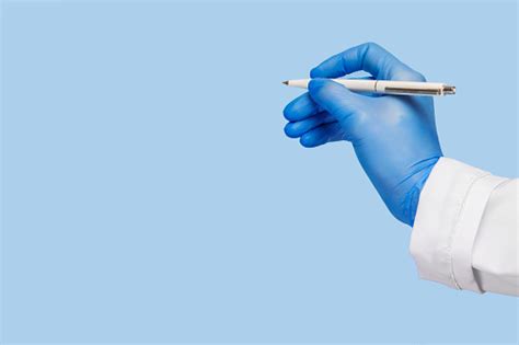 의료용 장갑을 끼고 흰 코트를 입은 여성의 손이 펜을 들고 파란색 배경에 공중에 쓰인다 간호사에 대한 스톡 사진 및 기타 이미지 간호사 개념 개념과 주제 Istock