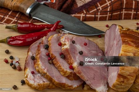 육즙이 많고 맛있는 베이컨 조각은 조각 칼 멀티 컬러 딸기 완두콩 붉은 고추 파슬리 딜 및 바질로 나무 도마에 맛있는 조각으로 자릅니다 고기 요리의 개념 건강한 식생활에