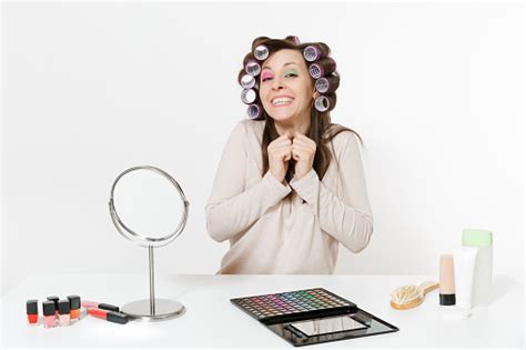 흰색 바탕에 격리 설정된 얼굴 장식 화장품으로 메이크업을 적용 하는 테이블에 앉아 머리에 컬러와 함께 재미 있는 젊은 여자 뷰티 여성 패션 라이프 스타일 개념입니다 영역