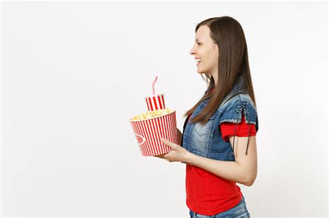 젊은 미소 매력적인 여자 영화 영화를 보고 팝콘의 물통 및 소 다 또는 콜라 흰색 배경에 고립 된 복사 공간에 따로 보고의 플라스틱 컵의 초상화 극장에서의 감정