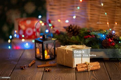 공예 종이로 싸인 선물이있는 상자와 황금 빛으로 장식 된 공으로 장식 된 크리스마스 트리가있는 크리스마스 휴가 배경 나무 테이블 클로즈업에 양초 12월에 대한 스톡 사진 및