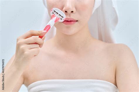 아시아 한국의 젊은 여자 모델이 앉아서 머리에 흰색 수건을 두르고 쇄골과 어깨라인이 보이는 브라탑을 입고 핑크색 면도기로