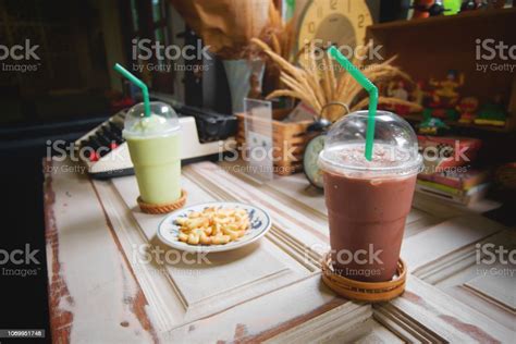코코아 투명 한 플라스틱 유리에 초콜릿과 그린 차 우유 프라 페가 있다 녹색 짚과 알파벳 쿠키 빈티지 카페에서 나무 선반에 0
