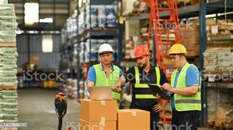 대형 창고의 랩톱 컴퓨터에서 재고 진드기 및 골판지 재고 제품을 검사하는 관리자 및 창고 작업자 25 29세에 대한 스톡 사진