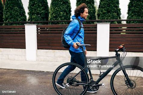 울타리 집 옆 비오는 날에 자전거를 타고 자전거를 타고 자전거를 타고 걷는 잘생긴 남자의 측면 보기 이미지 곱슬 머리를 가진