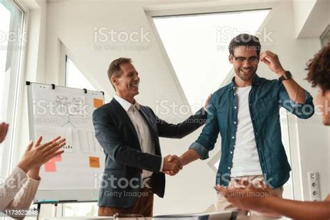 우리 팀에 오신 것을 환영합니다 현대 사무실에서 회의를 하는 동안 두 명의 쾌활한 동료가 악수하고 미소를 지으며 경영자에 대한 스톡 사진 및 기타 이미지 Istock