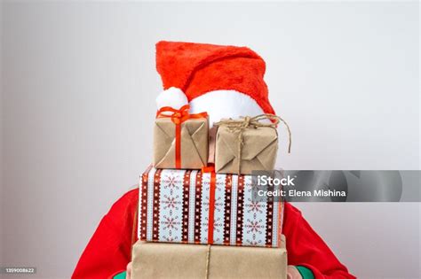 흰색 배경에 선물의 더미 뒤에 숨어 빨간 모자에 작은 산타 도우미 많은 선물을 들고 있는 아이 새해 축하 쇼핑 판매 선물 크리스마스 새해 광고 프로모션 12월에 대한 스톡