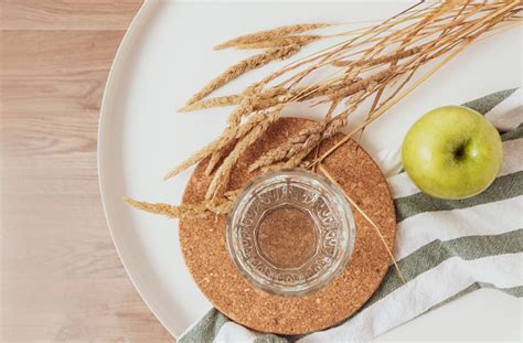 코르크 스탠드에 물 한 잔이 흰색 테이블에 서 있으며 옆에는 면 냅킨에 녹색 사과와 말린 꽃다발이 있습니다 적절한 영양 따뜻한