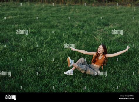 Young Woman Playing Games In The Park On The Green Grass Spreading Her