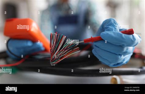 Master Repairman Testing Multicolored Wires From Cable Using Tester