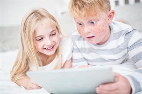 Premium Photo Brother And Babe Lying In Bed Using Tablet