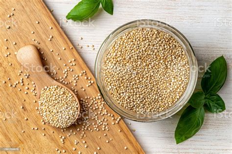 유리 항아리에 하얀 퀴노아 씨앗과 흰색 나무 테이블 위에 나무 숟가락 글루텐 프리 다이어트를위한 마른 퀴노아 곡물 Chenopodium Quinoa 슈퍼 푸드 개념 채식주의