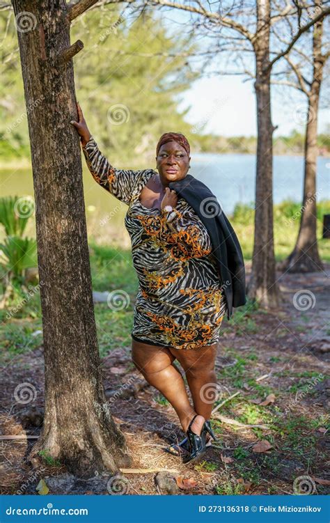 Beautiful Black Plus Sized Model Posing By A Tree In A Tranquil Park
