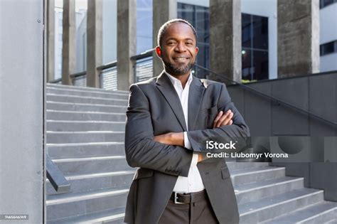성공적인 아프리카 계 미국인 사업가의 초상화 사무실 센터 밖에서 정장을 입고 서 있습니다 그는 자신있게 카메라를 바라보고 팔짱을 끼고 미소를 짓습니다 남자에 대한 스톡 사진