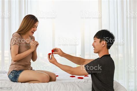 사랑 발렌타인 데이와 결혼 나 개념 결혼 약혼 반지와 빨간 상자를 들고 웃는 남자는 침실에서 행복 놀라게 감정적 인 여자 친구를