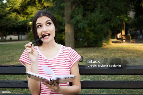 도 서와 공원에서 그녀의 입에 펜 생각 매력적인 소녀 인간의 감정 메모장에 대한 스톡 사진 및 기타 이미지 메모장 줄무늬 T 셔츠 Istock