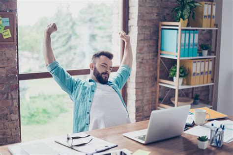 퇴근 후 피곤 한 남자는 그의 워크 스테이션에서 자신의 노트북 화면 앞 휴식의 자 머리 위 팔 홈 오피스 윈도우와 뒤에 벽돌