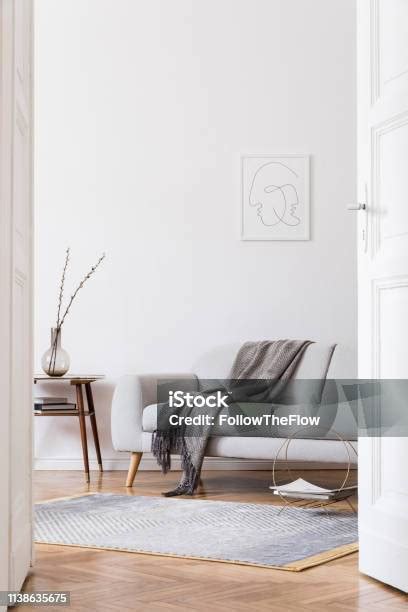 디자인 회색 소파와 레트로 작은 테이블과 홈 공간의 세련 된 Scandi 인테리어 디자인 액세서리와 모의 포스터 프레임이 있는 거실 우아한 장식으로 꾸며져 있습니다 현대