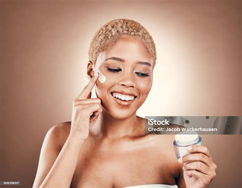 모이스처라이저 제품 크림 흑인 여성이 스튜디오에서 뷰티 스킨케어와 페이스 로션으로 미소를 짓고 있다 갈색 배경 얼굴에 화장과 피부 광채를 가진 모델의 고립된 콜라겐 피부과