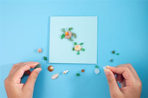 밝은 파란색 종이 조개 녹색 유리 조각 조개 껍질을 놓는 손 해변 장면 만들기 수제 공예 어린이 예술 프로젝트 자연 재료 Diy Diy에 대한 스톡 사진 및 기타 이미지