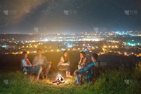 在星空背景下，人们把手放在篝火旁休息。晚上的时间素材 花瓣网