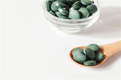 천연 첨가물과 슈퍼 푸드 흰색 배경에 숟가락과 유리 그릇에 녹색 스피루리나 조류 알약 건강한 개념유기농 식품 복사 공간 가루로 빻은에 대한 스톡 사진 및 기타 이미지